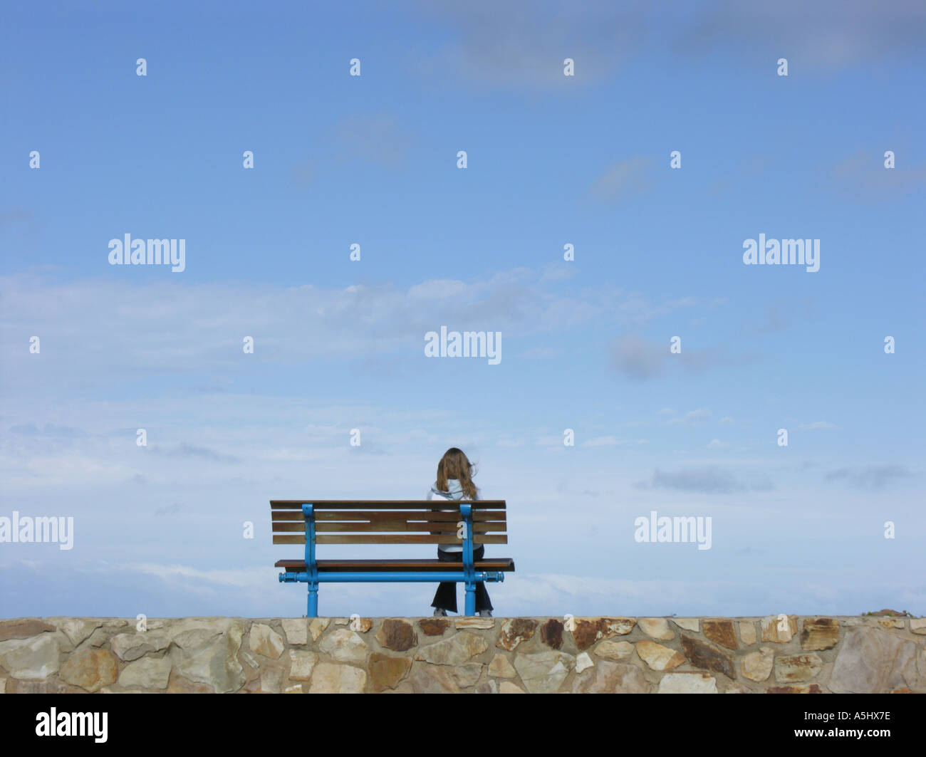 Young girl sitting on bench watching clouds Stock Photo - Alamy