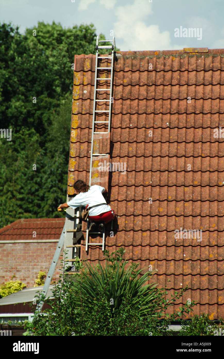 Roof tile repairs in progress at verge to detached house Stock Photo ...