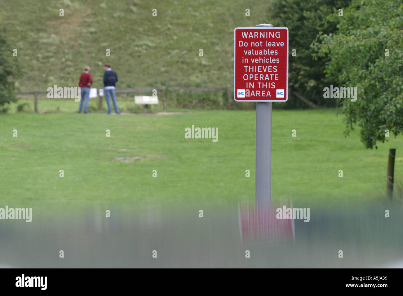 Sign warning of car thieves in the area reflected in a vehicle roof and ...