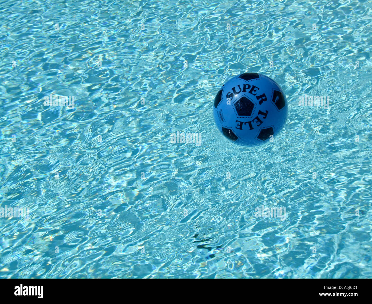 Blue football floating in pool Stock Photo - Alamy