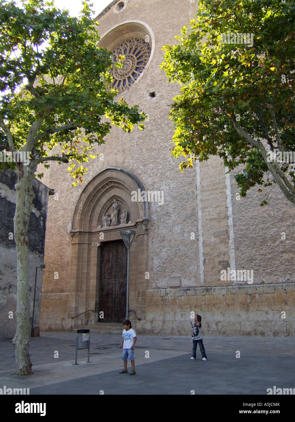 Children playing in square outside church in Pollenca town, Mallorca ...