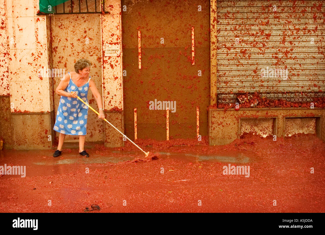 An old woman cleans up after the tomatina tomato festival in Buñol ... An old woman cleans up after the tomatina tomato festival in Buñol ...