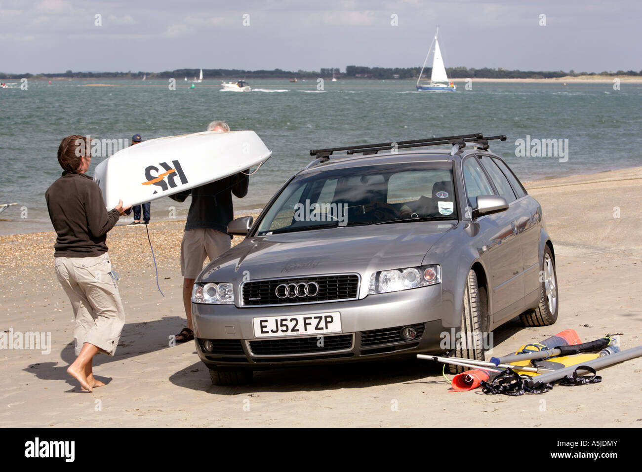 couple loading sailing dinghy on to roof of car Stock Photo - Alamy