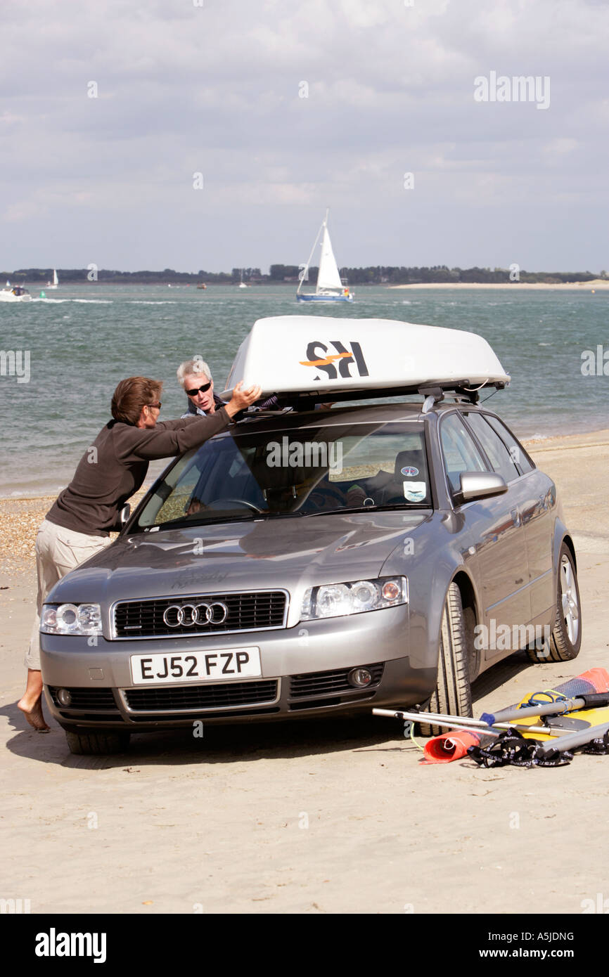 couple loading sailing dinghy on to roof of car Stock Photo - Alamy