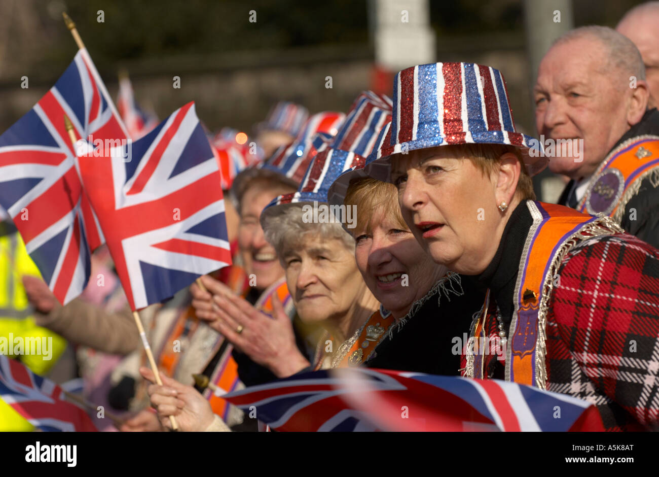 Orangemen and women with union jack flags watching the Orange Order ...