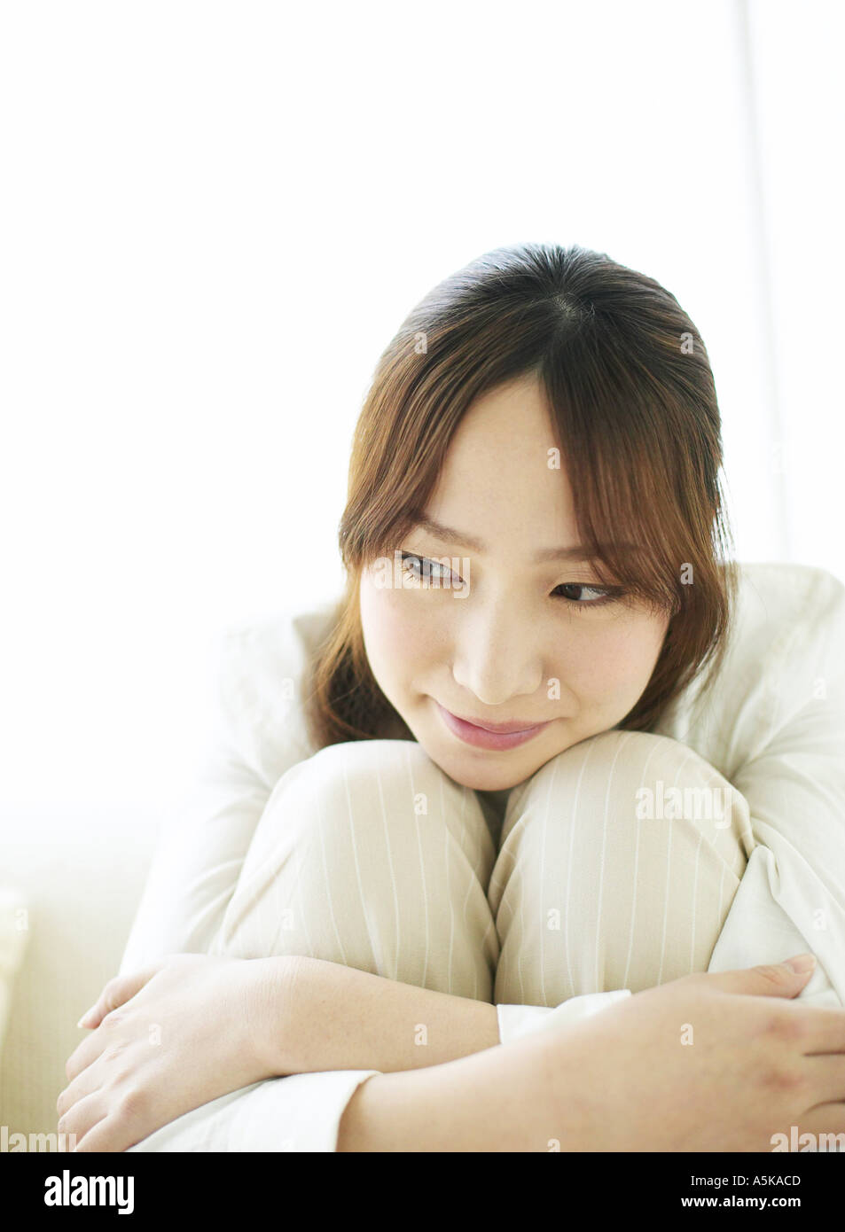 Young woman sitting hugging her knees Stock Photo - Alamy