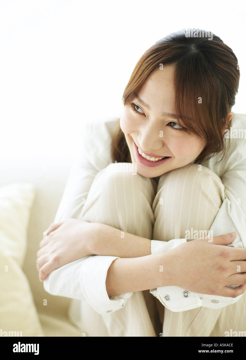 Young woman sitting hugging her knees Stock Photo - Alamy