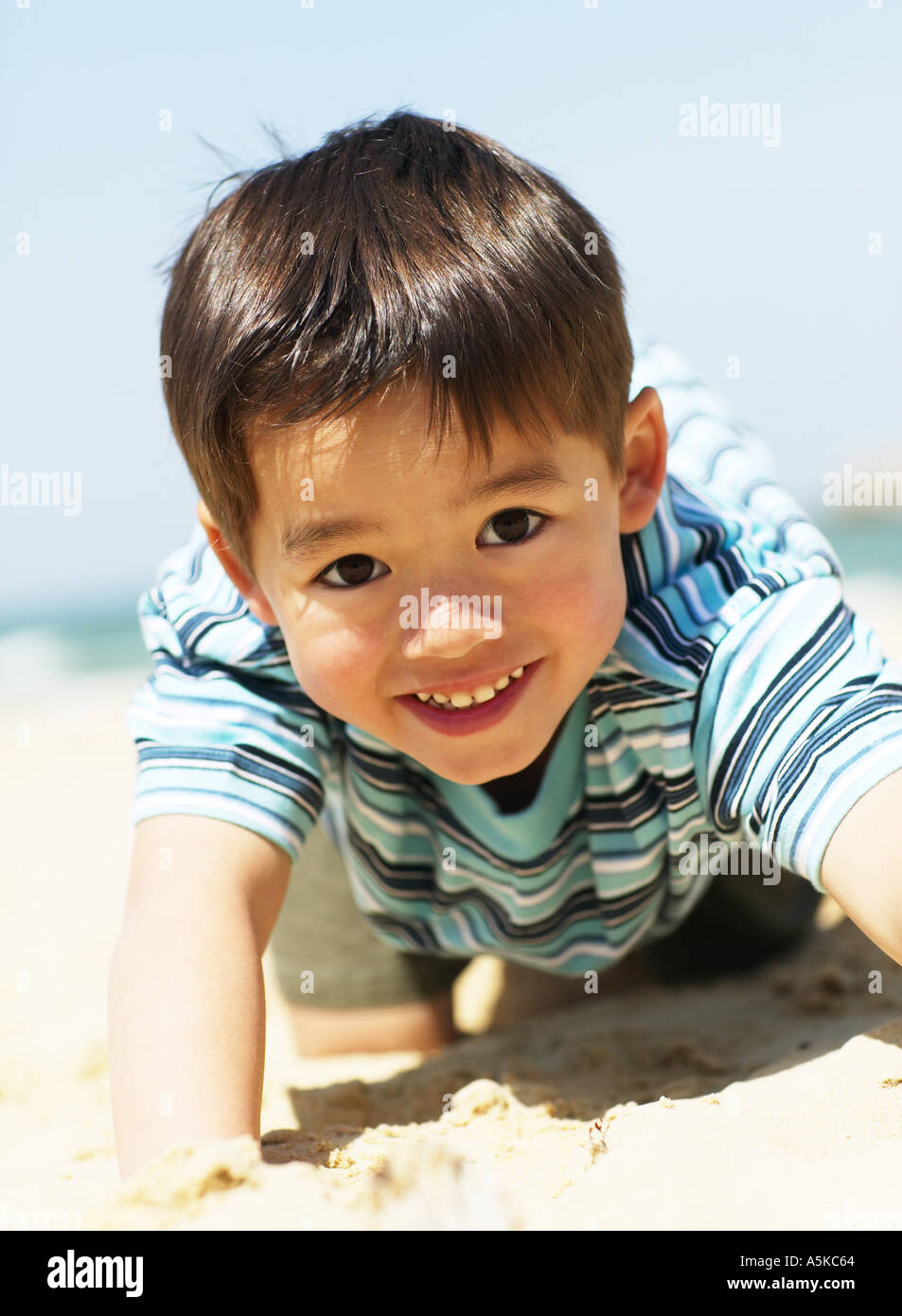 Young boy lying in sand and smiling Stock Photo - Alamy
