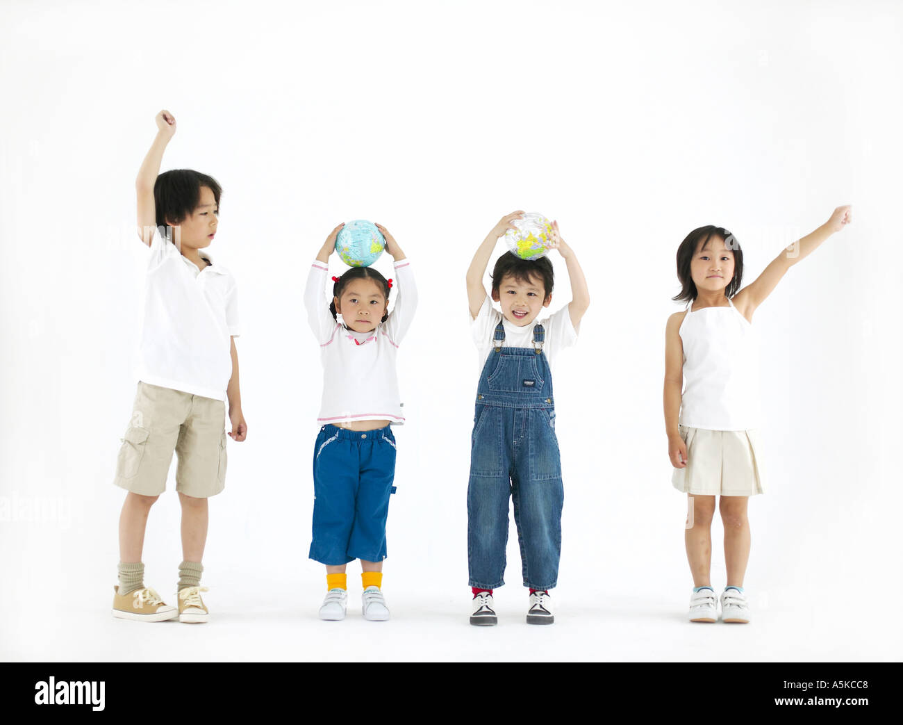 Young children standing with hands over head and smiling Stock Photo ...