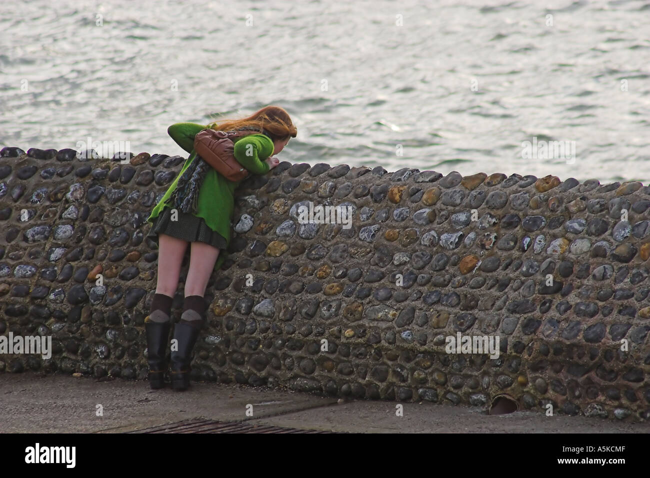 A girl peering over a sea wall Stock Photo - Alamy