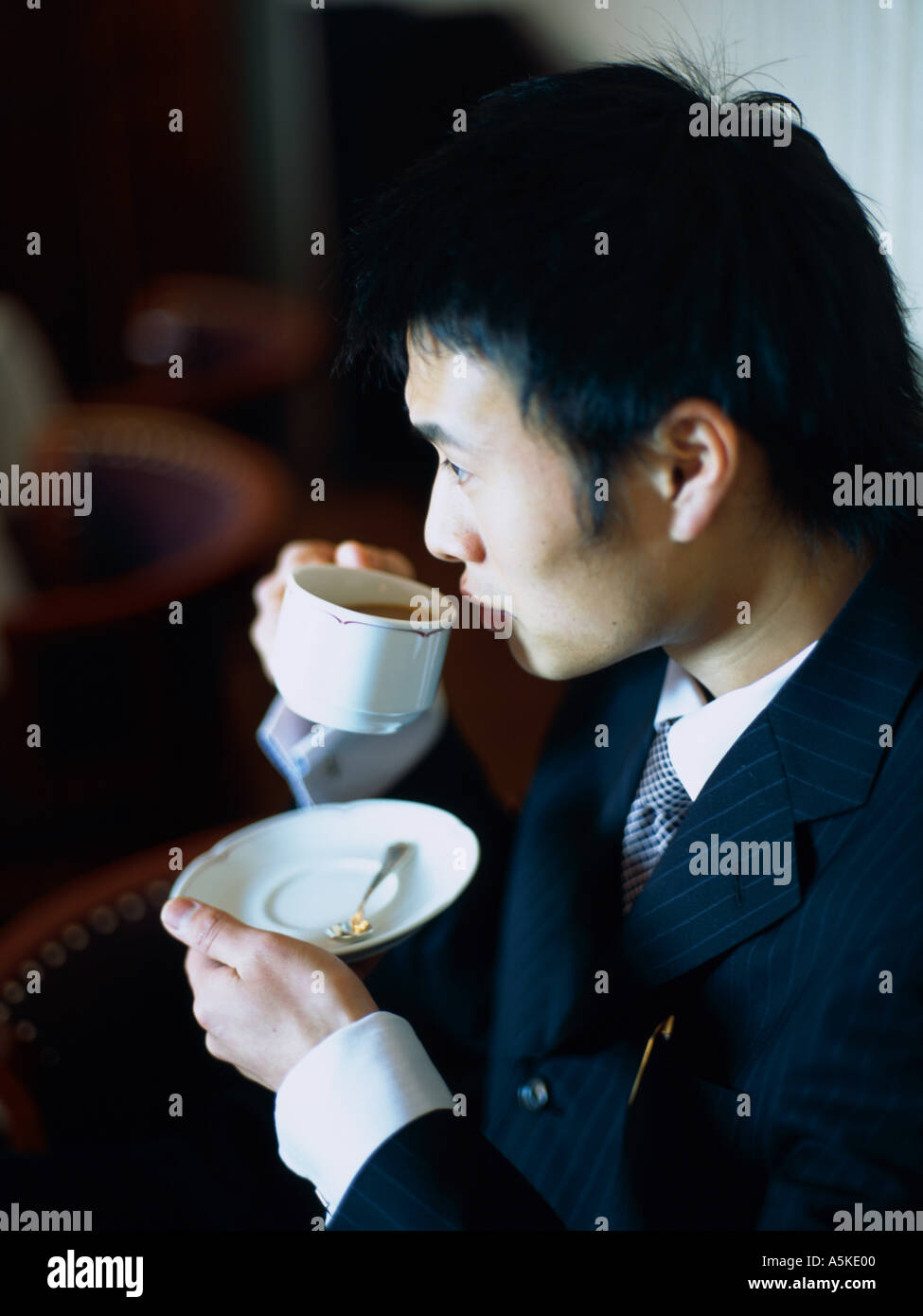 Asian Man sipping tea at a café Stock Photo - Alamy