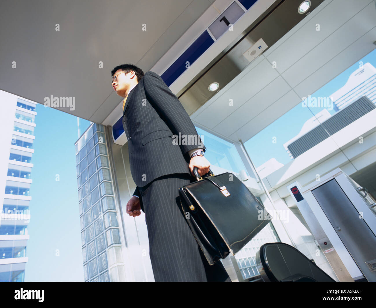 Asian Man walking out of an office Stock Photo - Alamy