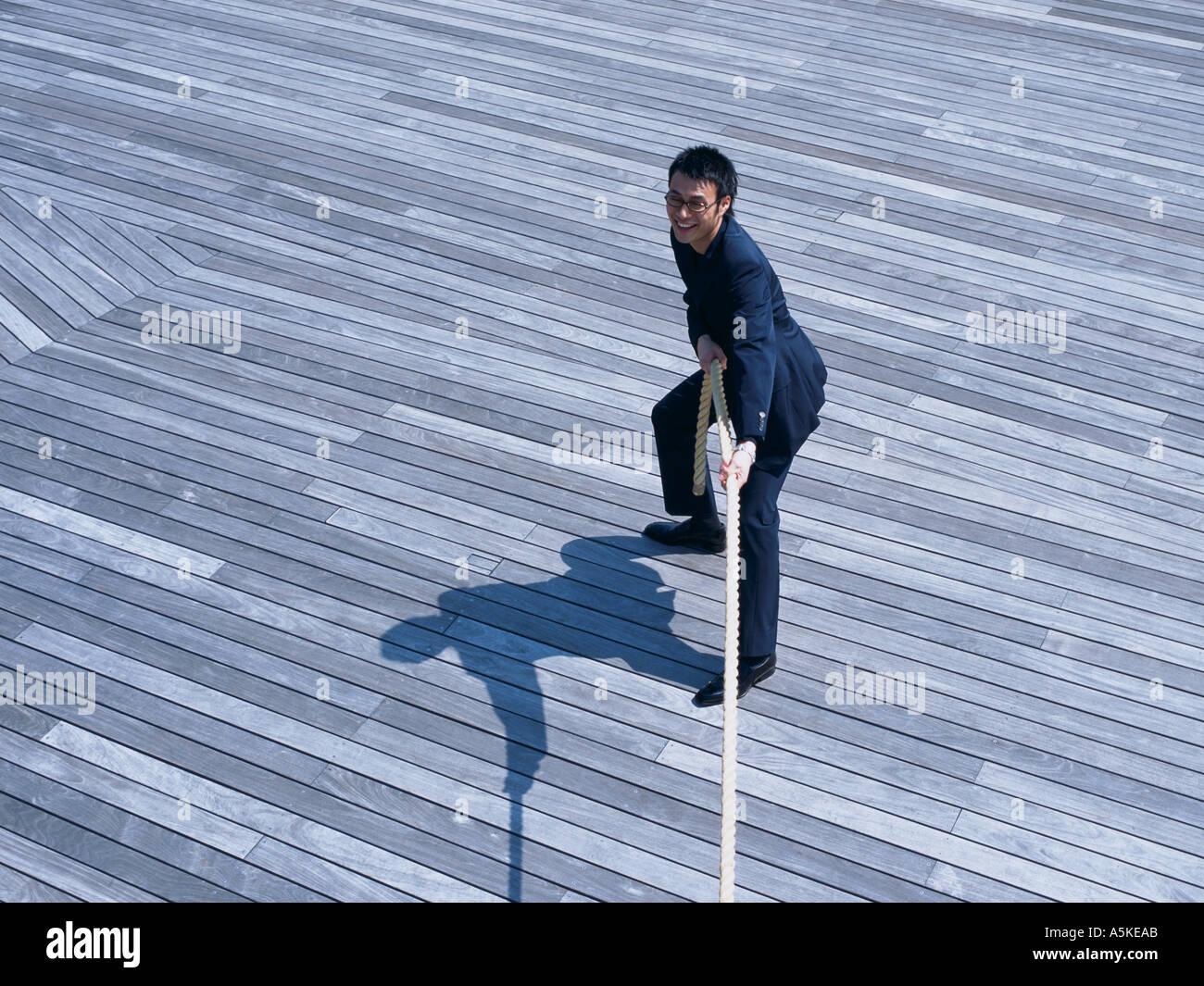 Asian Man pulling at a rope Stock Photo - Alamy