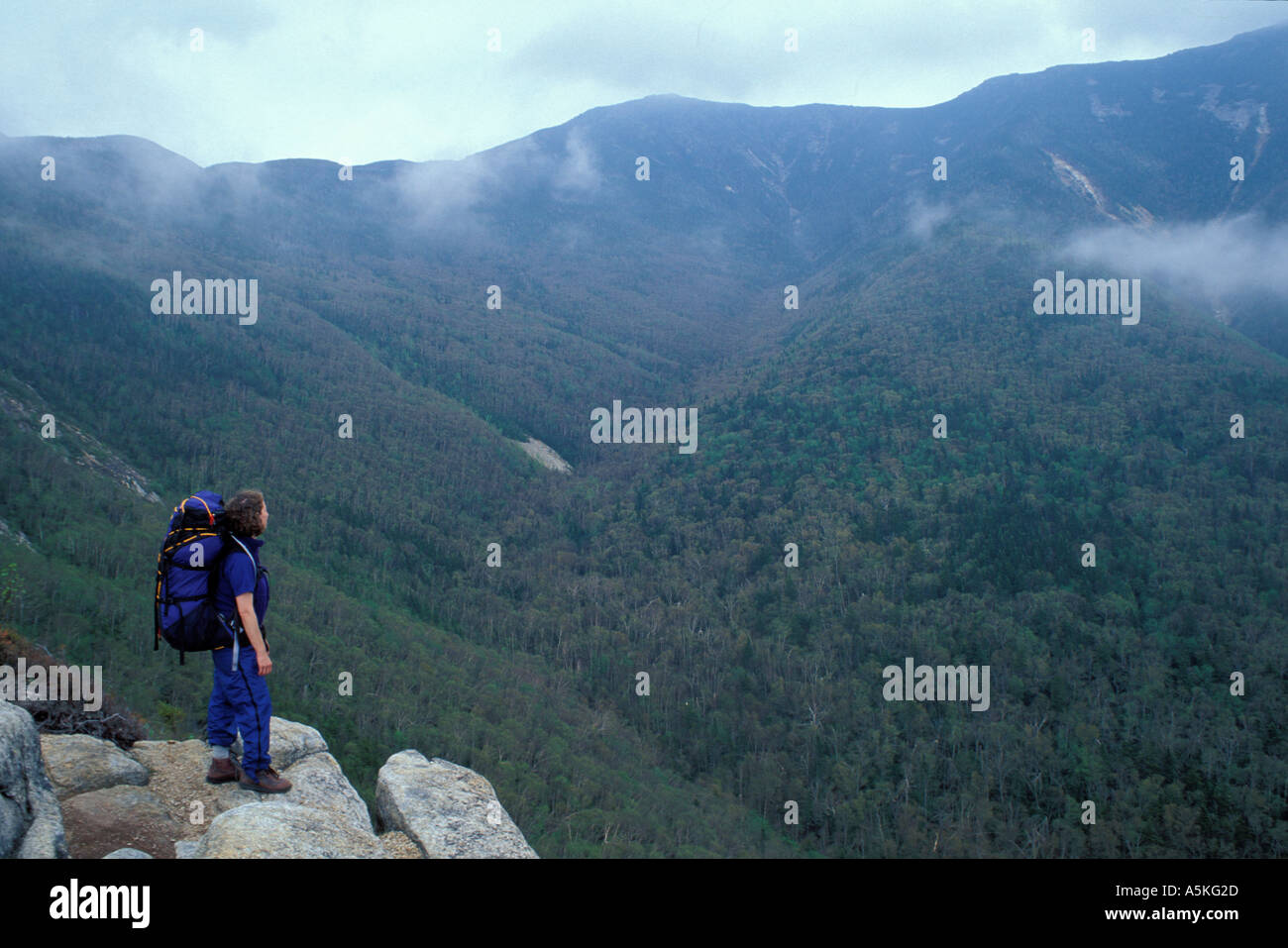 A hiker stands on the ledge with a view of the Franconia Ridge in the ...