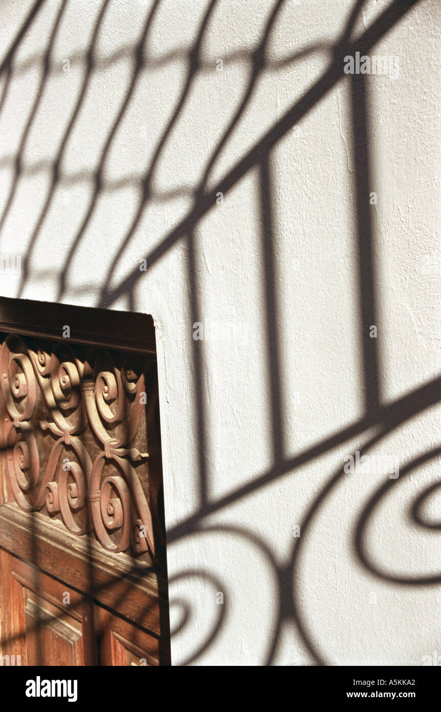 wrought iron gate shadow on wall and old door Stock Photo - Alamy