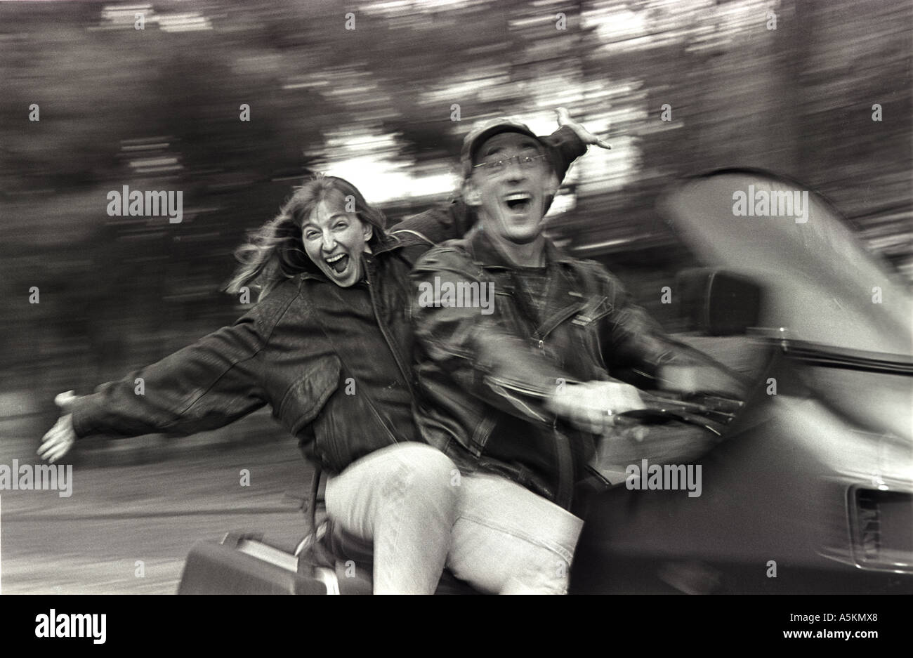 An excited couple grin wildly as they zoom past on a motorcycle Stock ...
