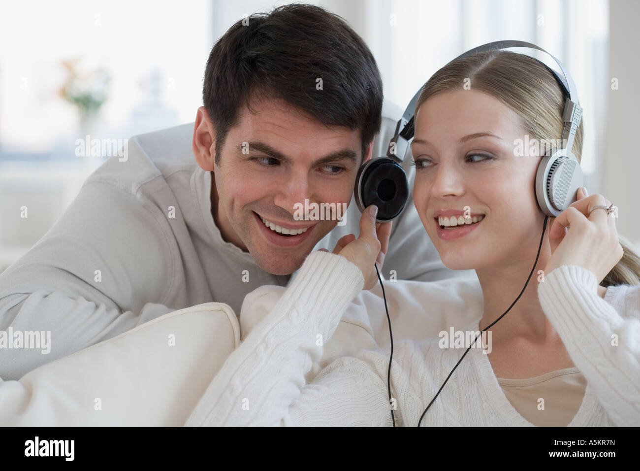Woman sharing headphones with husband Stock Photo - Alamy
