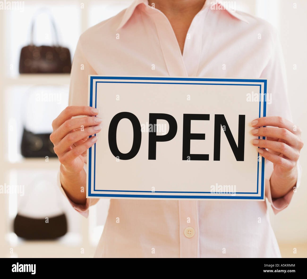 Woman holding Open sign in boutique Stock Photo - Alamy