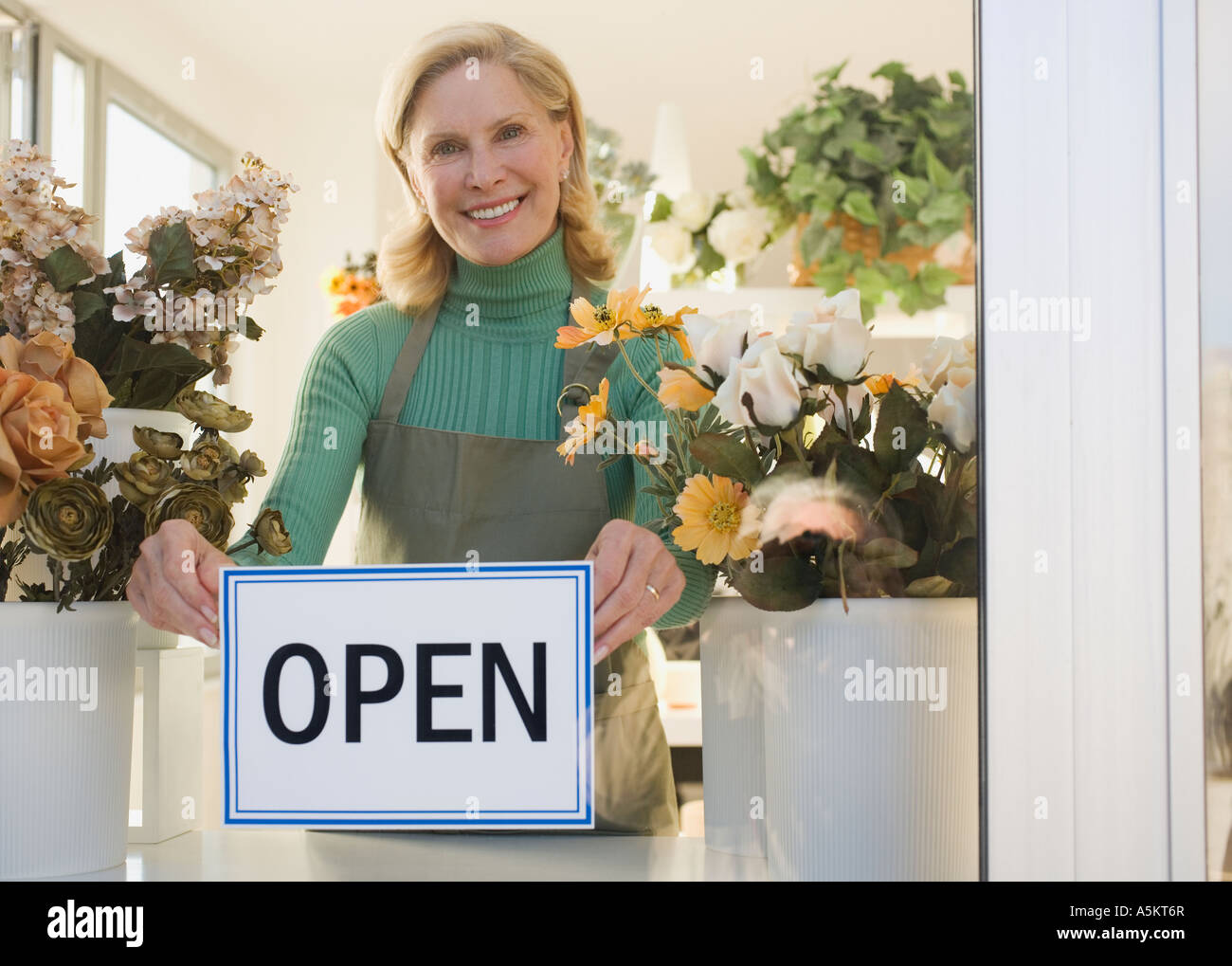 Female florist hanging Open sign in window Stock Photo - Alamy