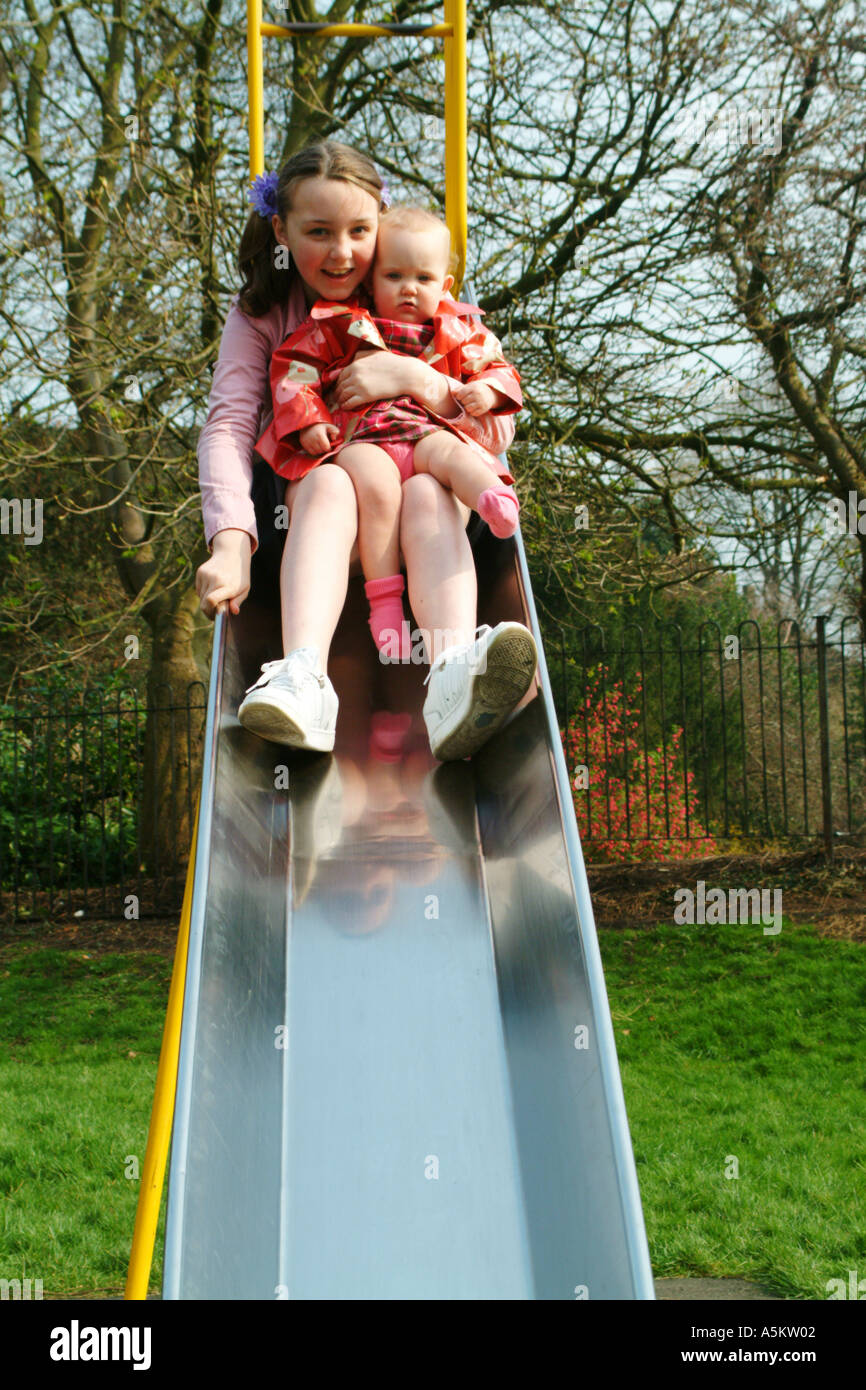 two girls on a slide in a playground Stock Photo - Alamy