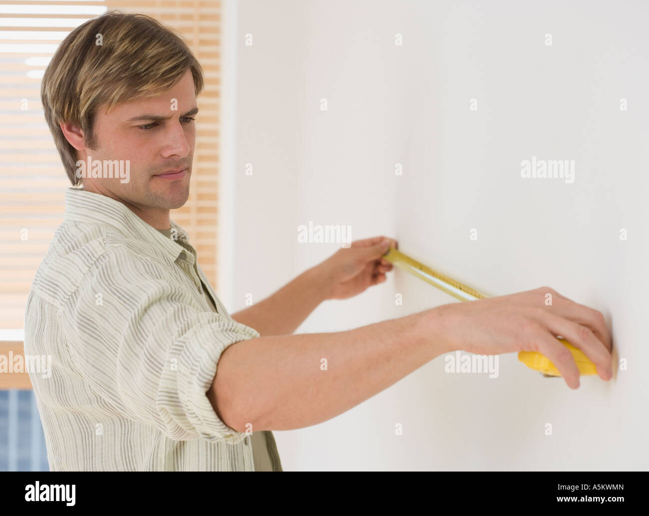 Man measuring wall with tape measure Stock Photo - Alamy