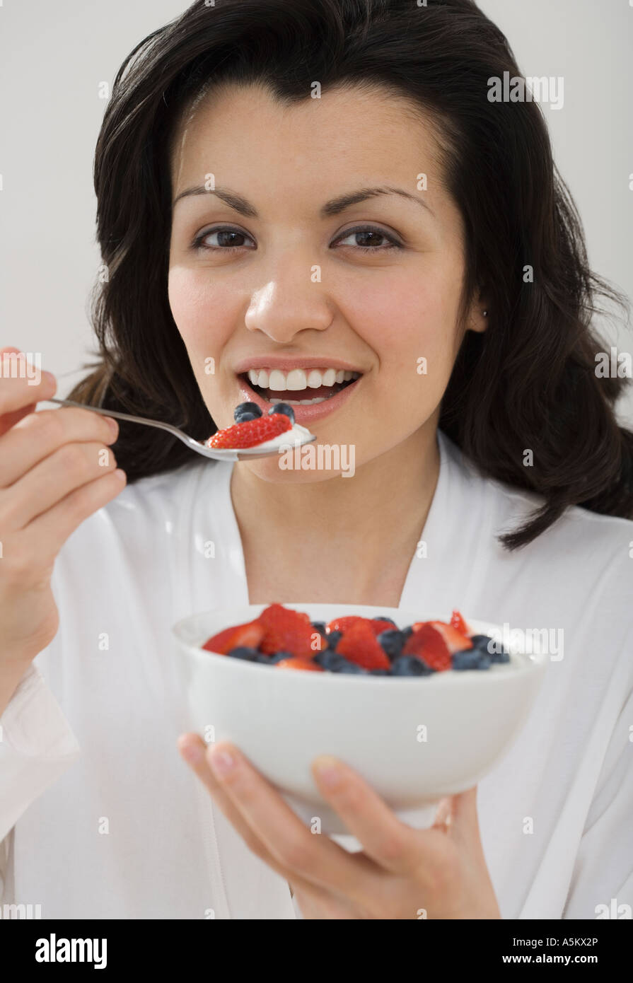 Woman eating bowl of fruit Stock Photo - Alamy