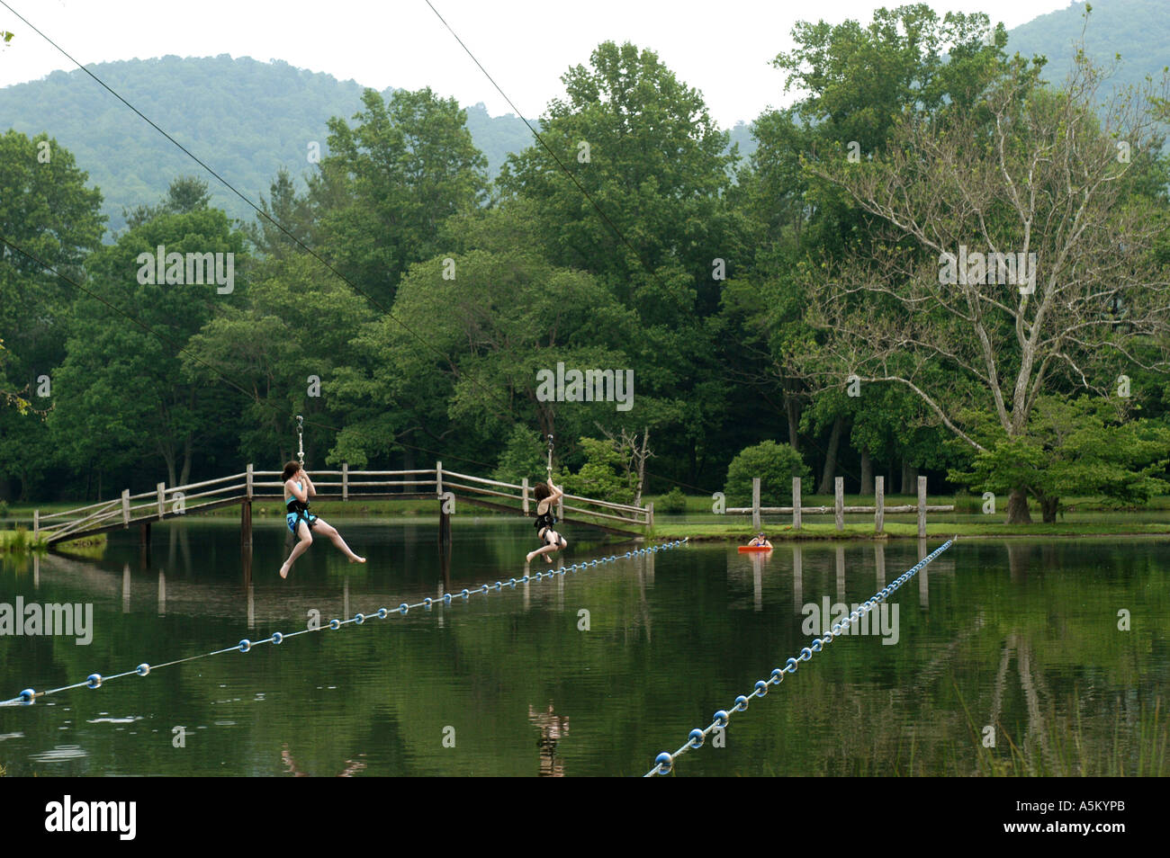 Two girls ride a zip line from a high level that makes them go very ...
