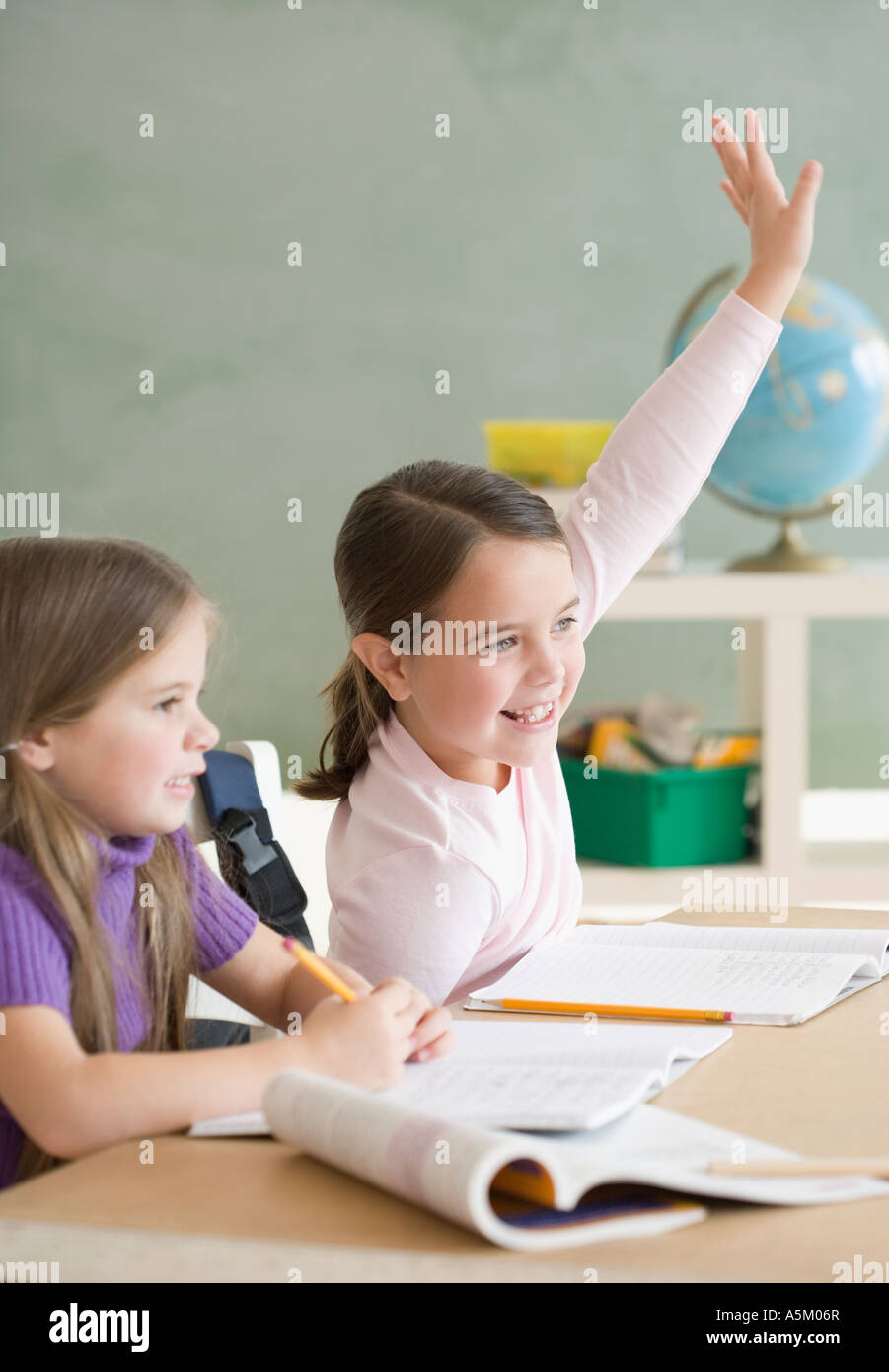 Girl raising hand in classroom Stock Photo - Alamy