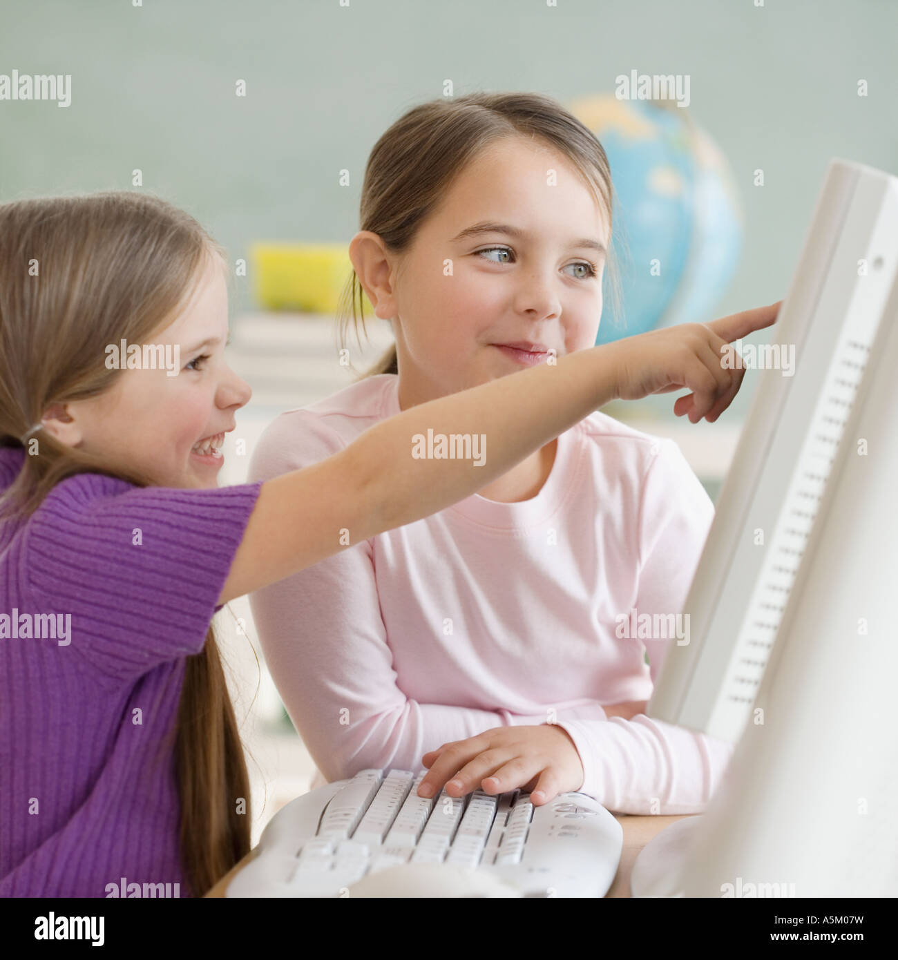 Two girls looking at computer in classroom Stock Photo - Alamy
