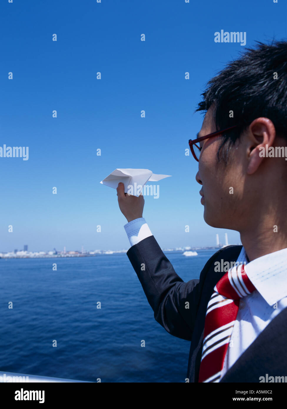 Asian Man throwing a paper plane overboard Stock Photo - Alamy
