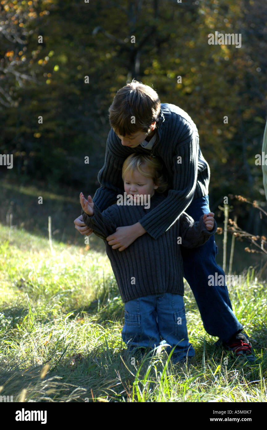A boy helps his younger brother pull his sleeves up on his sweater as ...