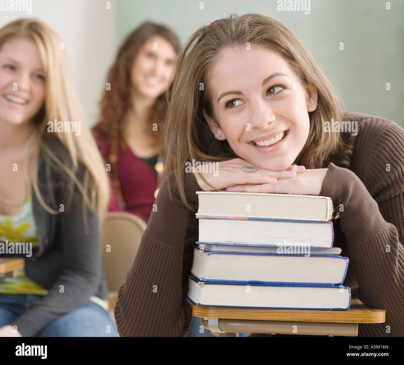Female student leaning on stack of books Stock Photo - Alamy
