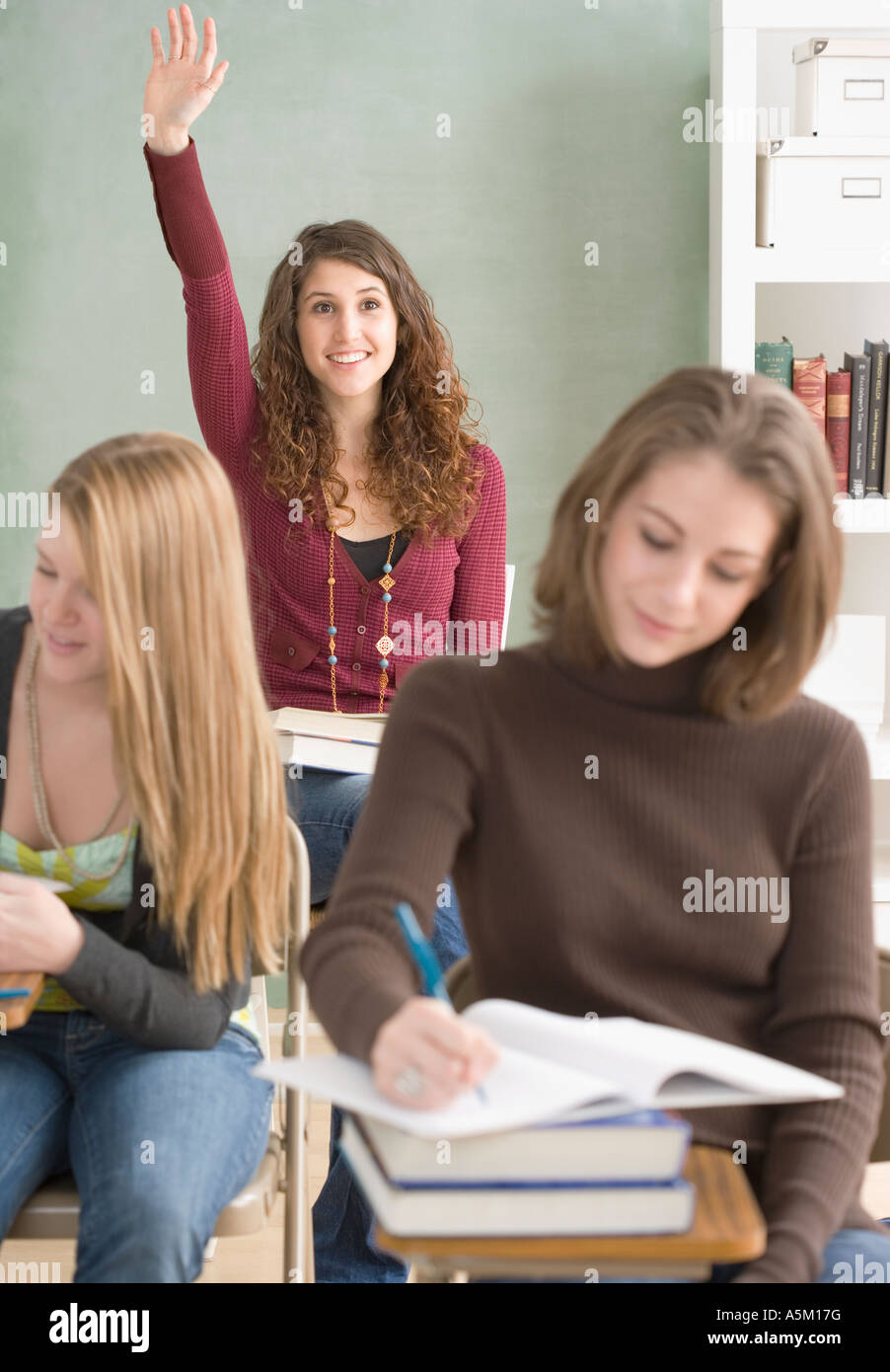 Female student raising hand in classroom Stock Photo - Alamy