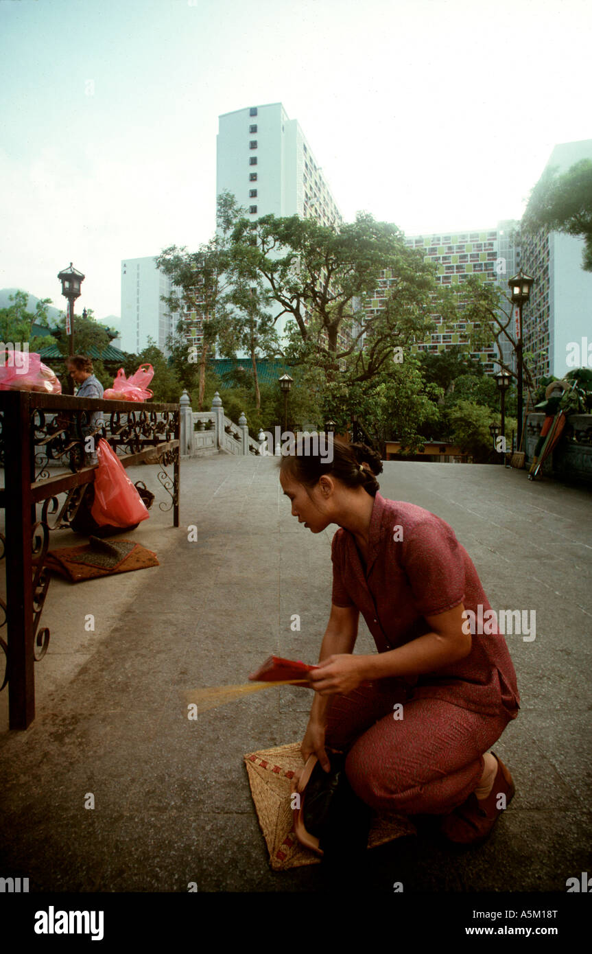 A woman kneels to offer her first prayer just inside the temple gates ...