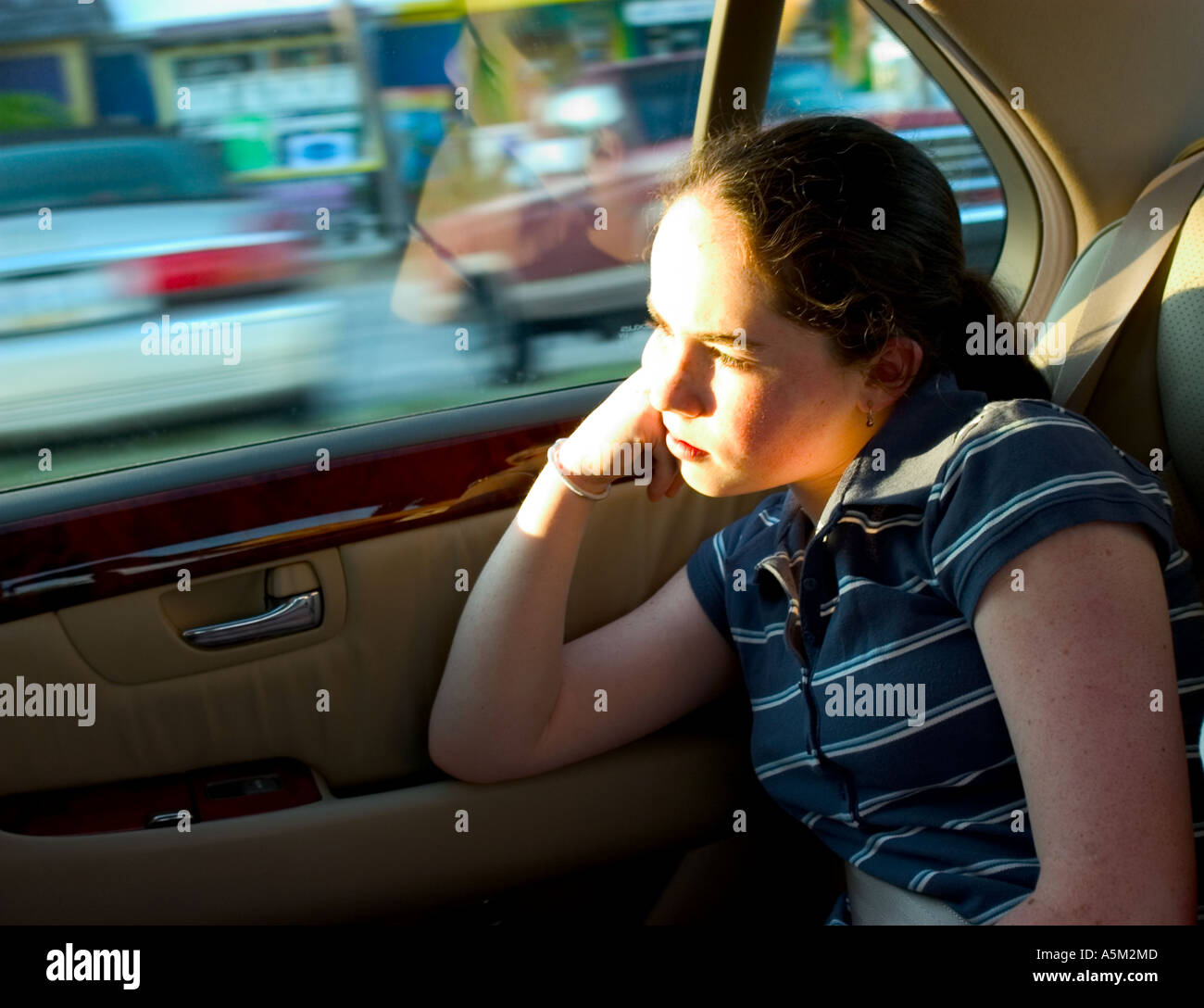 a thirteen year old girl is slumped against the car door looking out ...