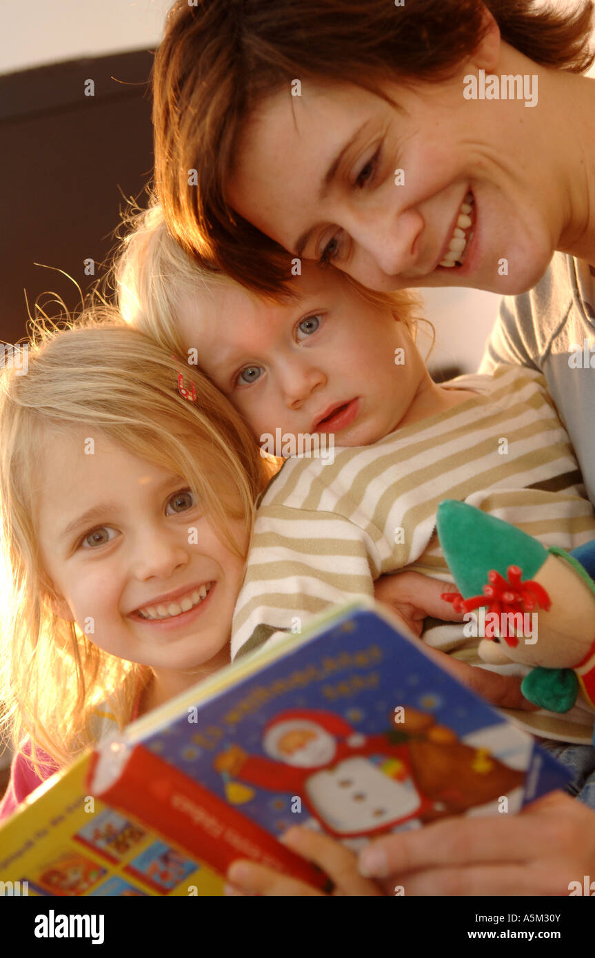 Young german mother with her two beautiful girls reading a book Stock ...