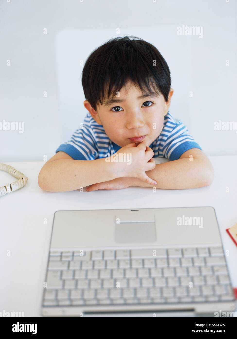 Asian child looking up from a desk Stock Photo - Alamy