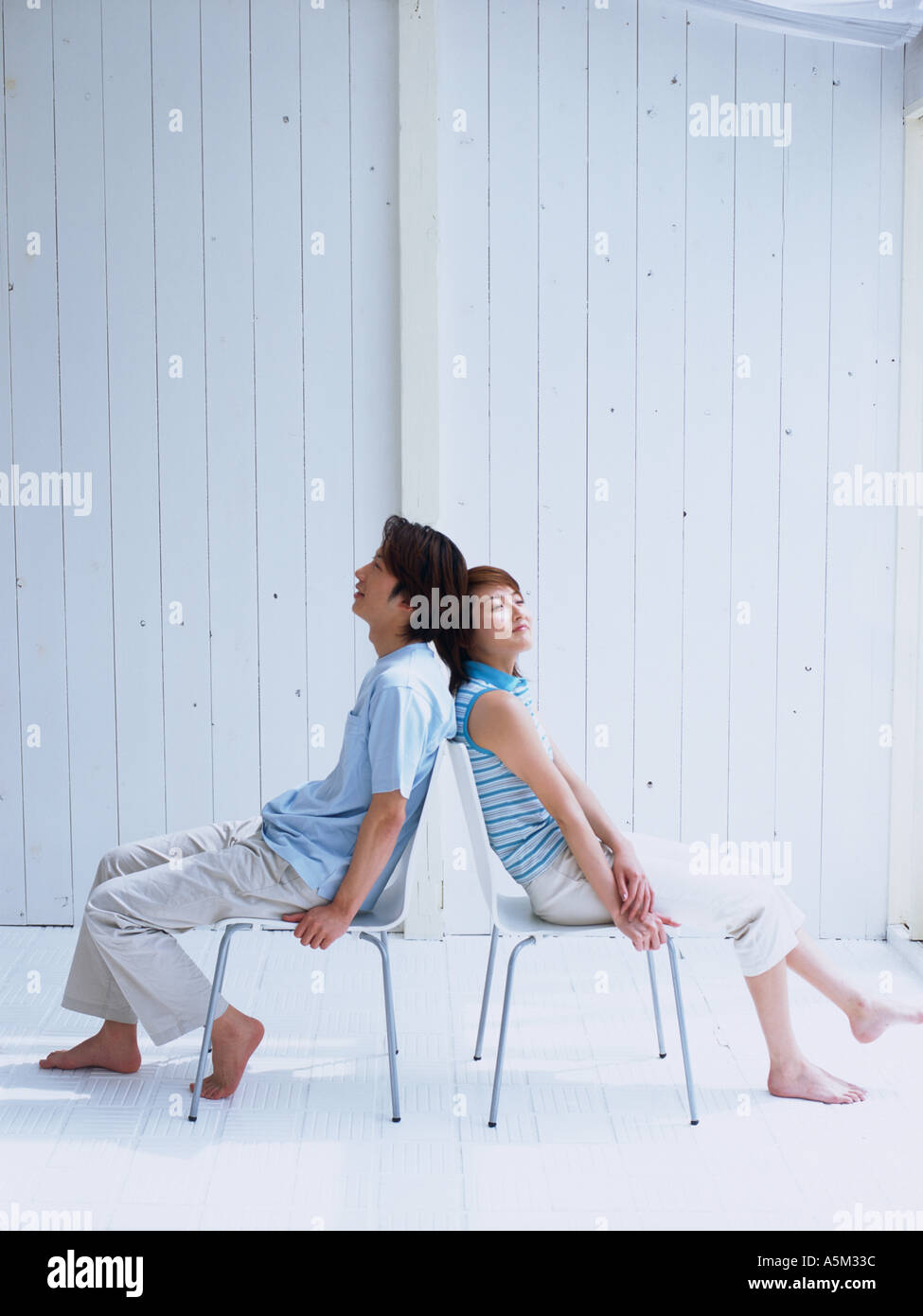 Asian couple sitting with their backs to each other Stock Photo - Alamy