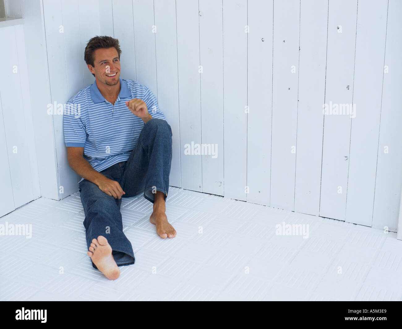 Caucasian man sitting on the floor Stock Photo - Alamy