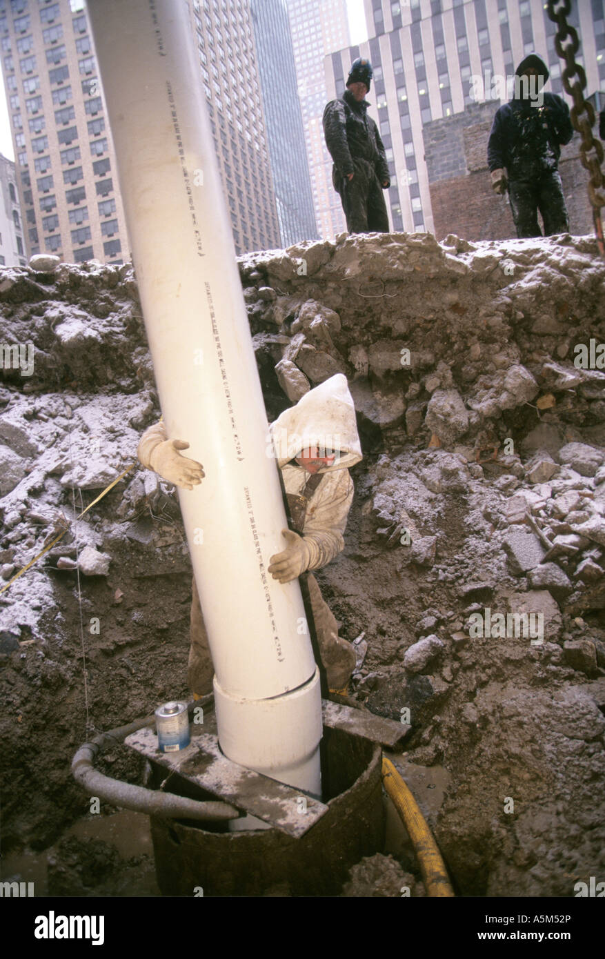 Worker installing pipe for drain in cold and snow in what will be ...