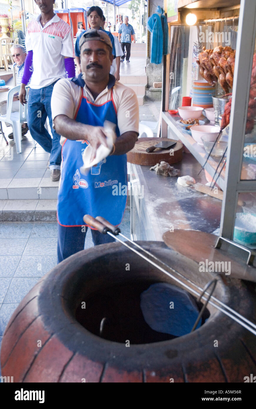 An Indian chef making naan bread in a Tandoori oven in Tanah Rata in ...