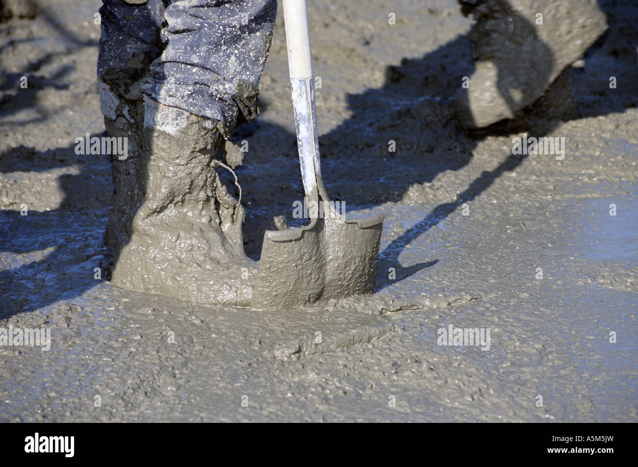 Boots covered with heavy concrete as workers pour concrete for floors ...