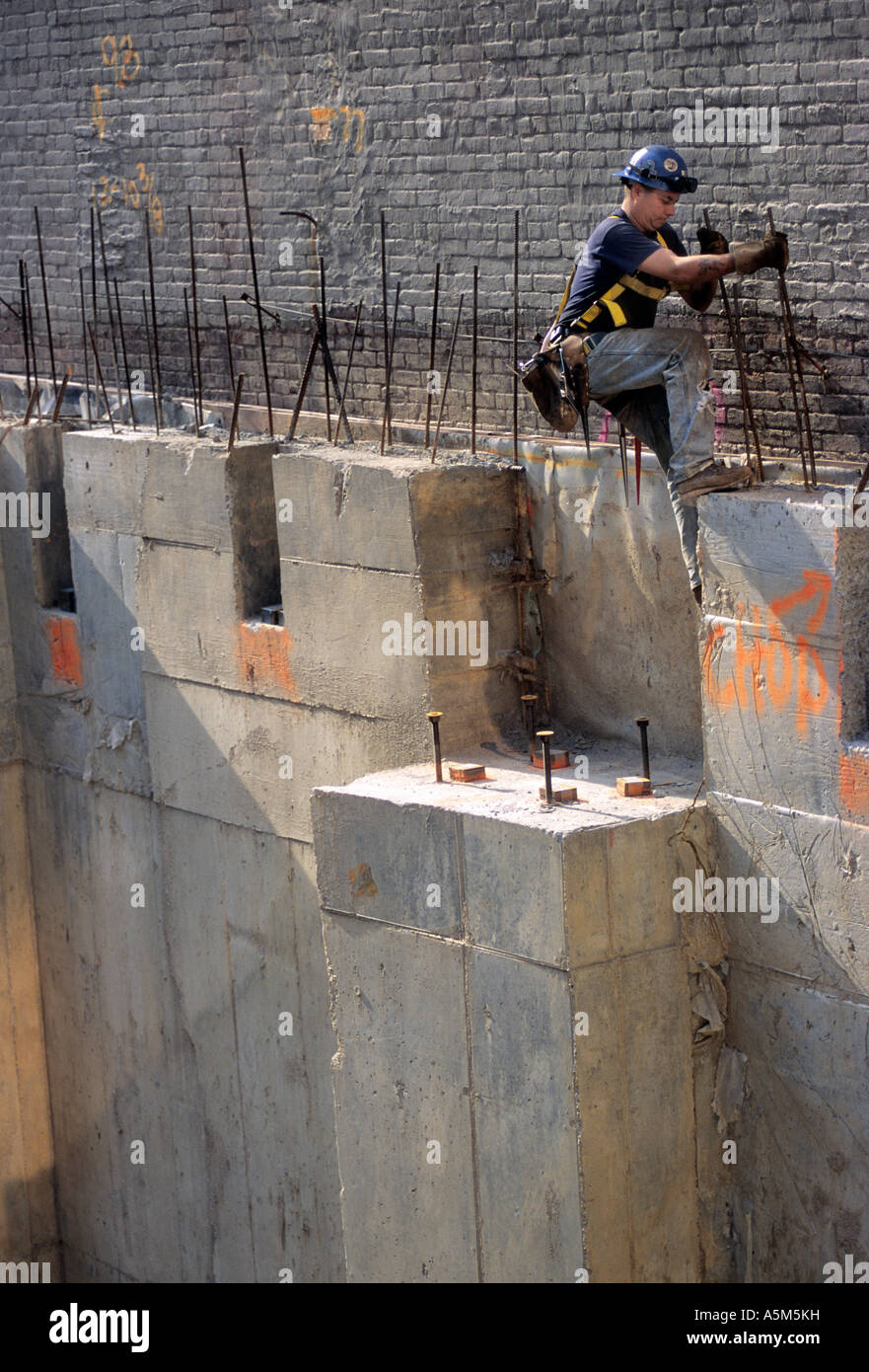 Iron worker climbs on new foundation that abuts neighboring building in ...