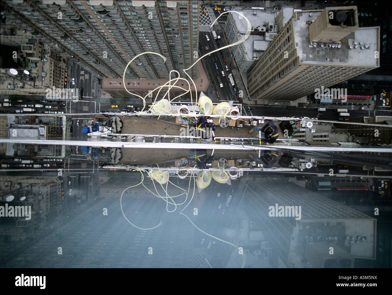 View of workers installing yellow caulk ropes on curtain wall at Random ...