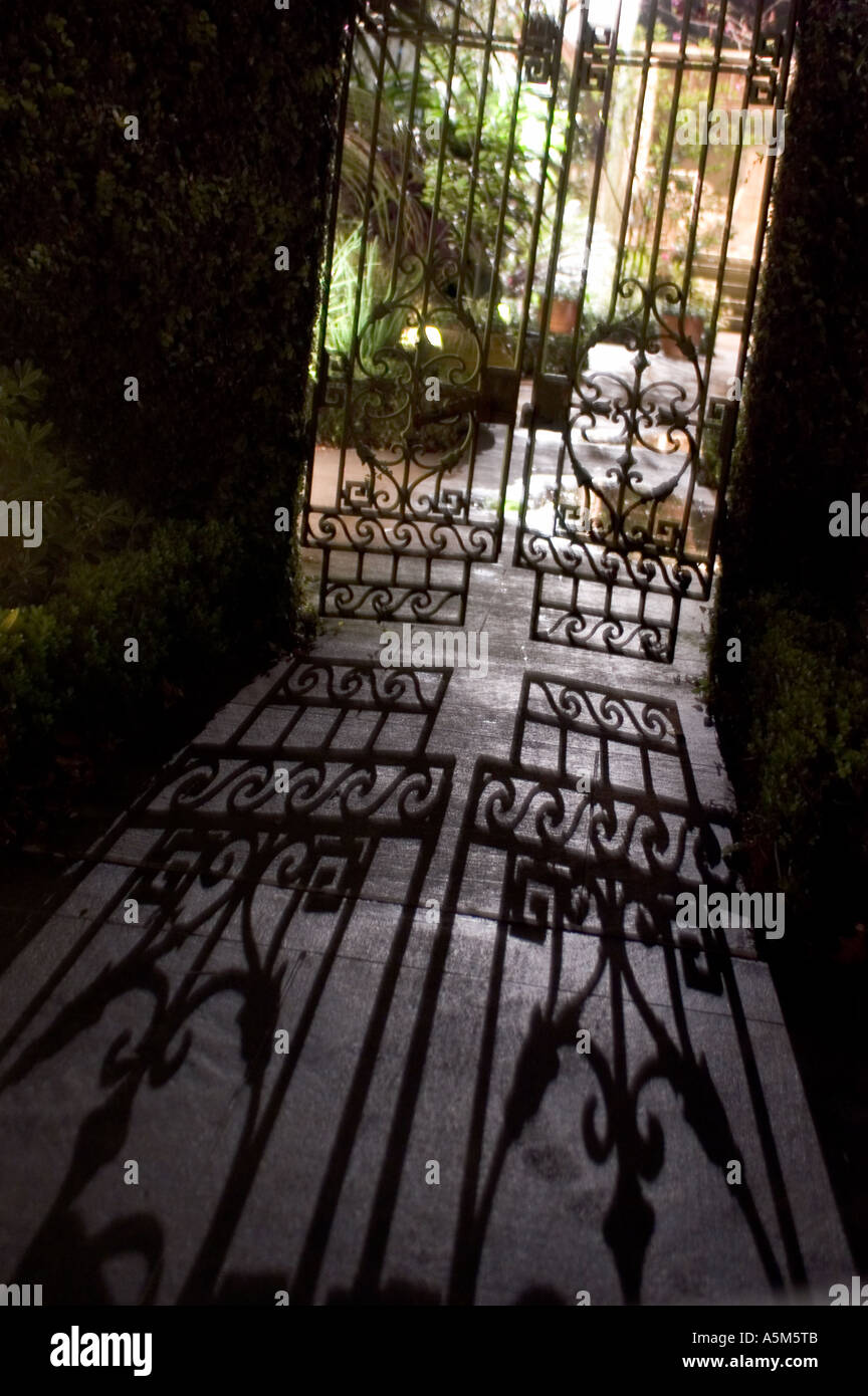 A light shining through old wrought iron gates cast eerie shadows in ...