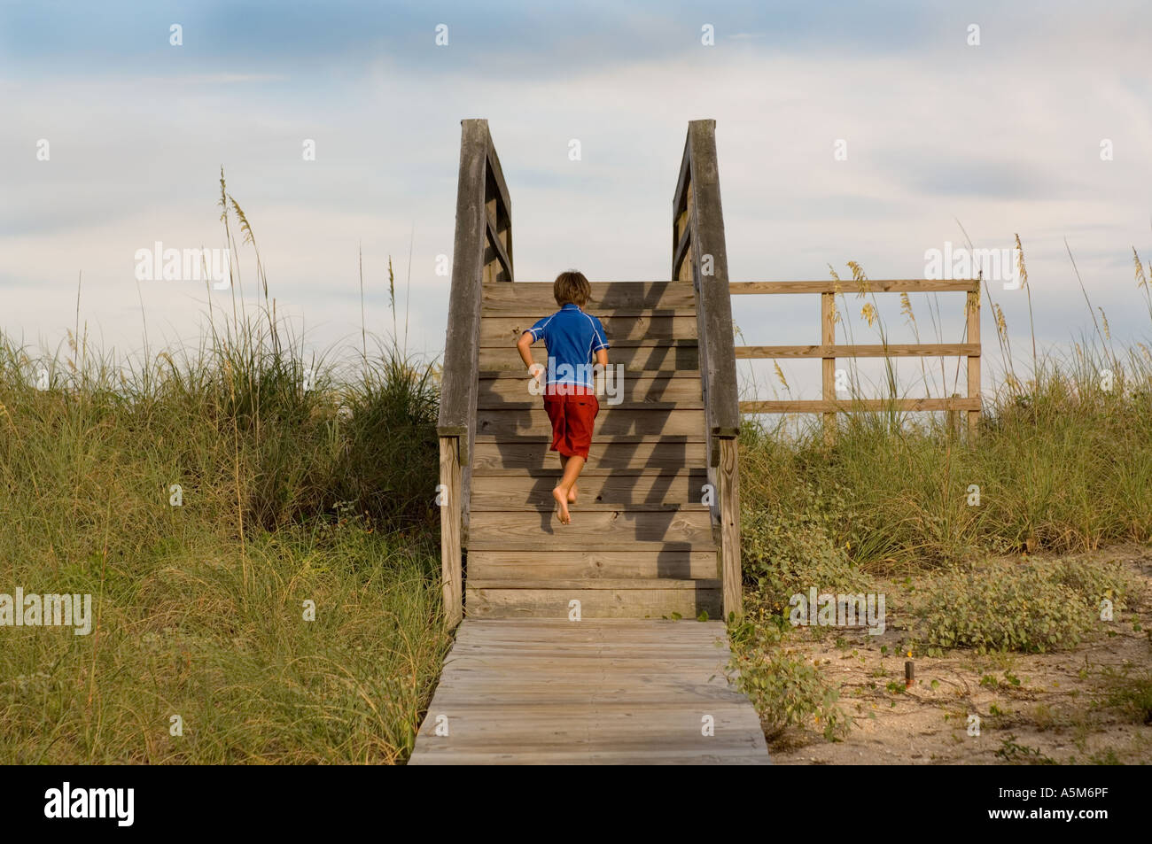 A young eight year old boy runs away from the viewer as he jumps up the ...