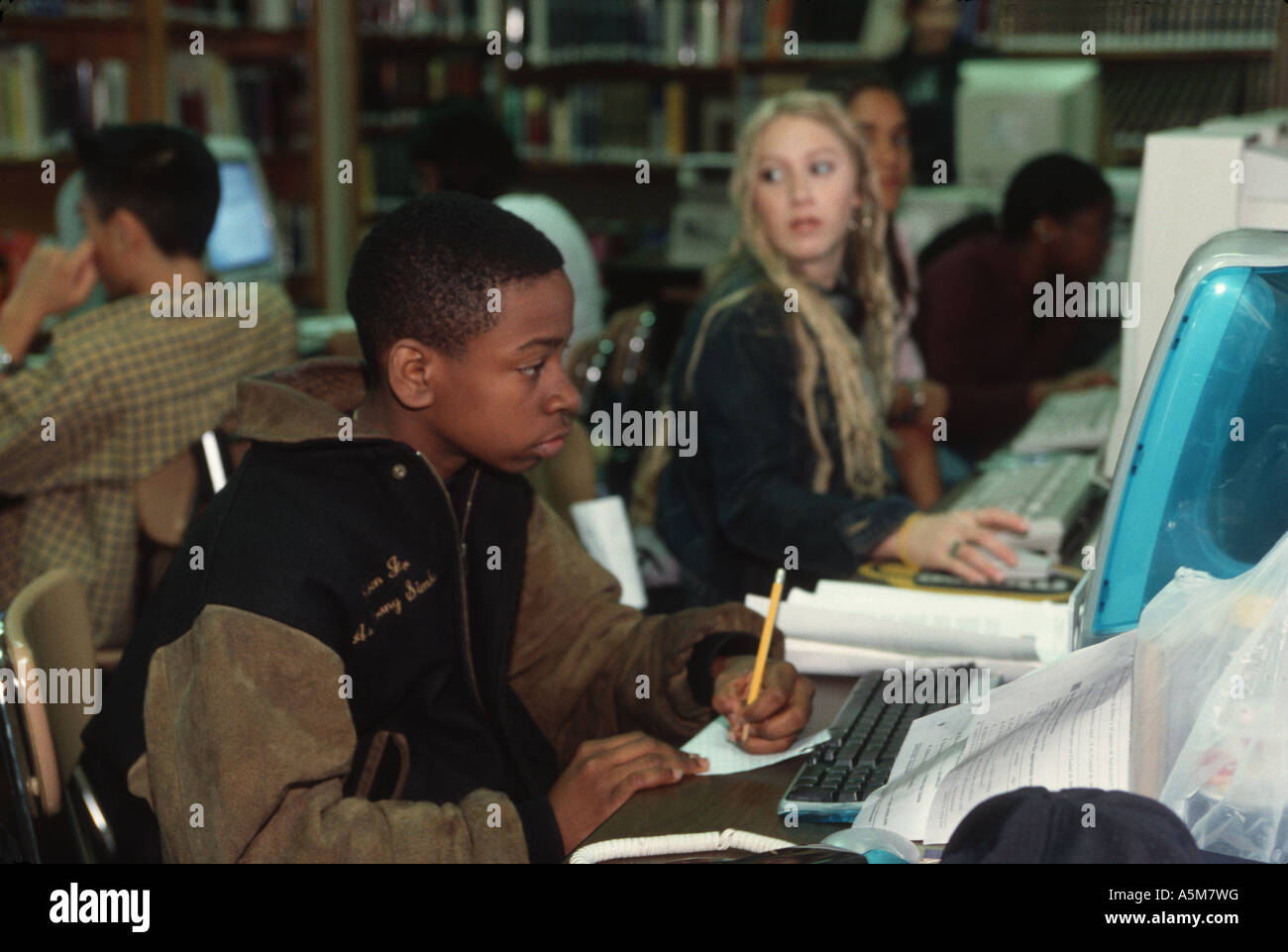 High school students work at computers doing homework at school library ...