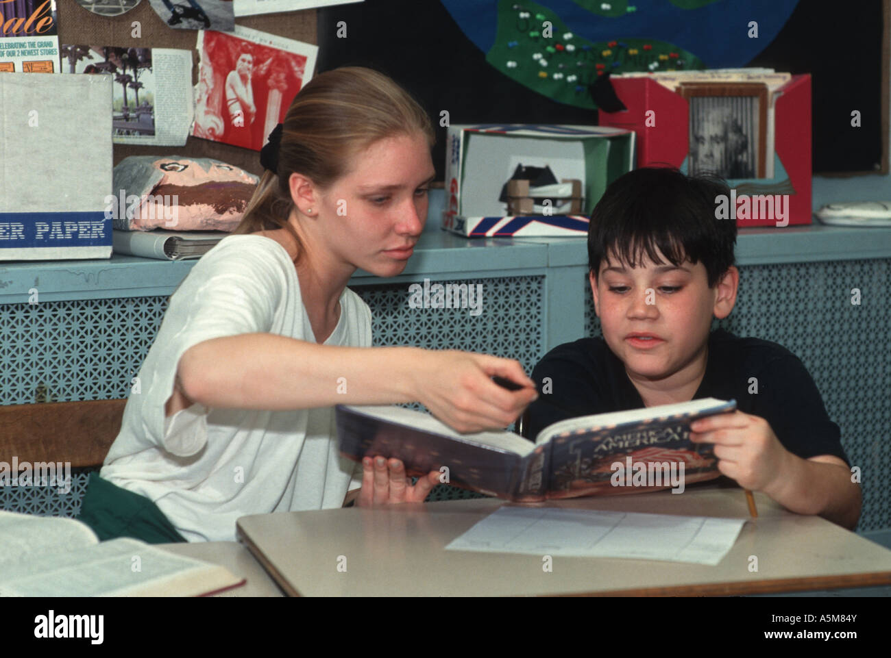 High school teen volunteer tutors an elementary school student as part ...