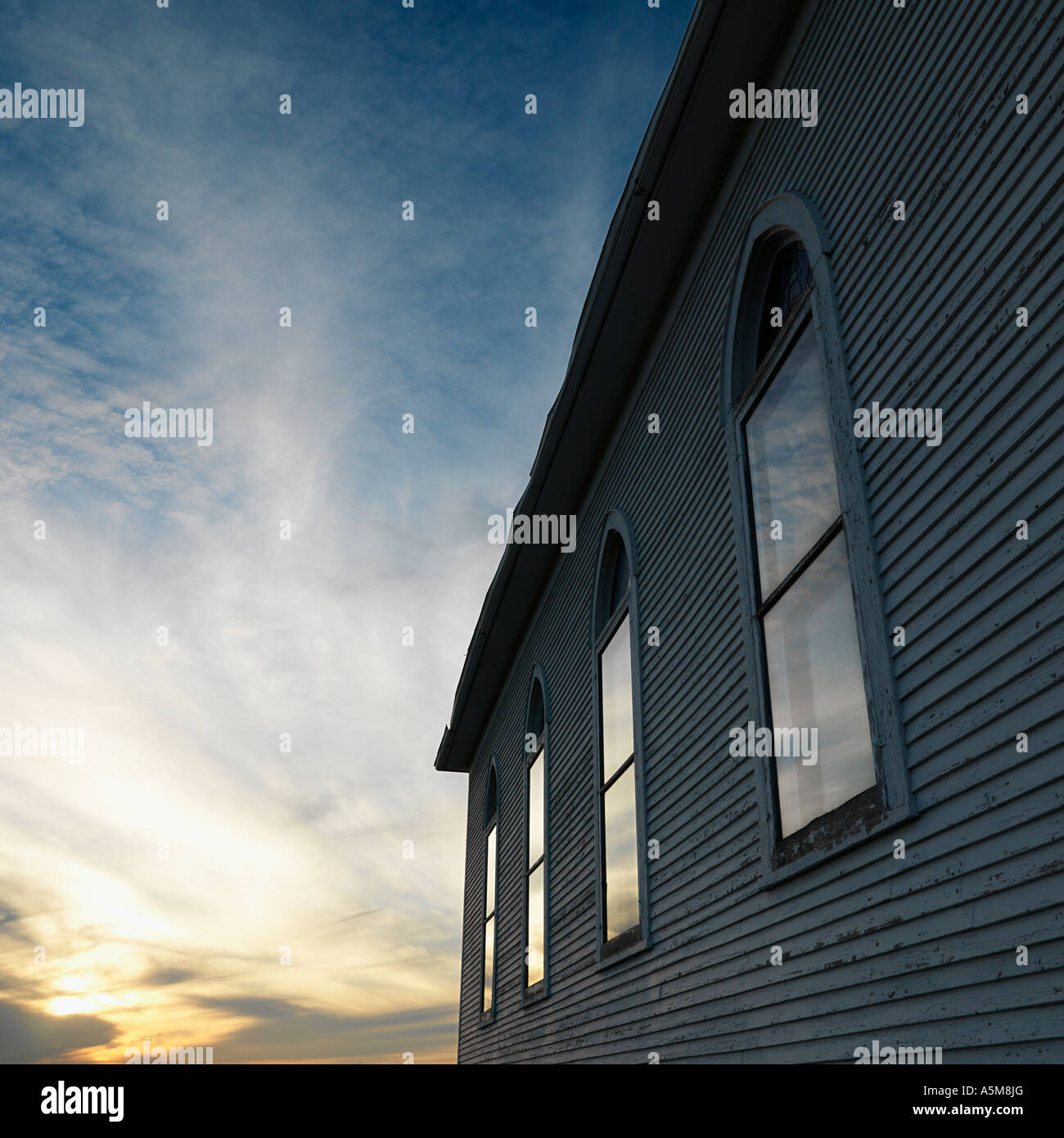 Sunset and clouds behind side view of building with arched windows and ...
