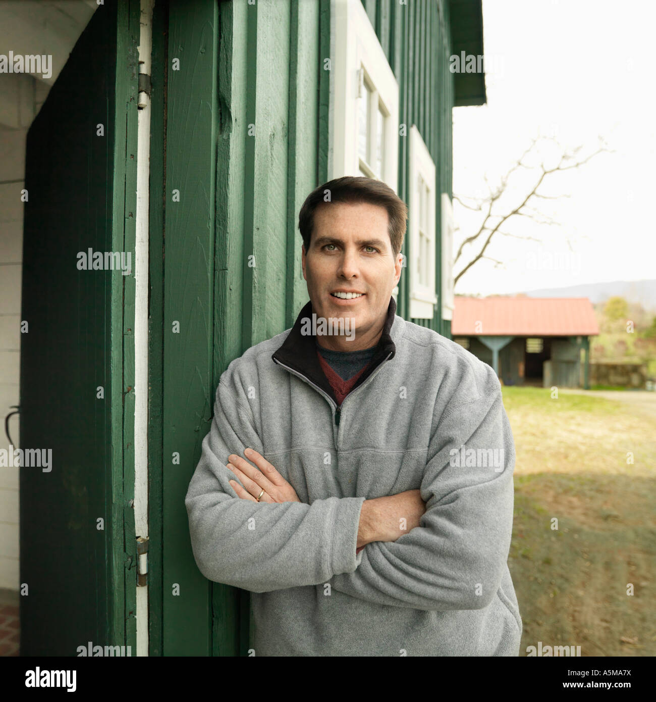 Caucasian man leaning against building smiling in rural setting Stock ...